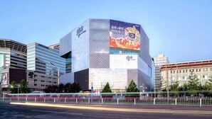 Um edifício moderno com fachada geométrica distinta, grandes janelas e um outdoor de destaque.