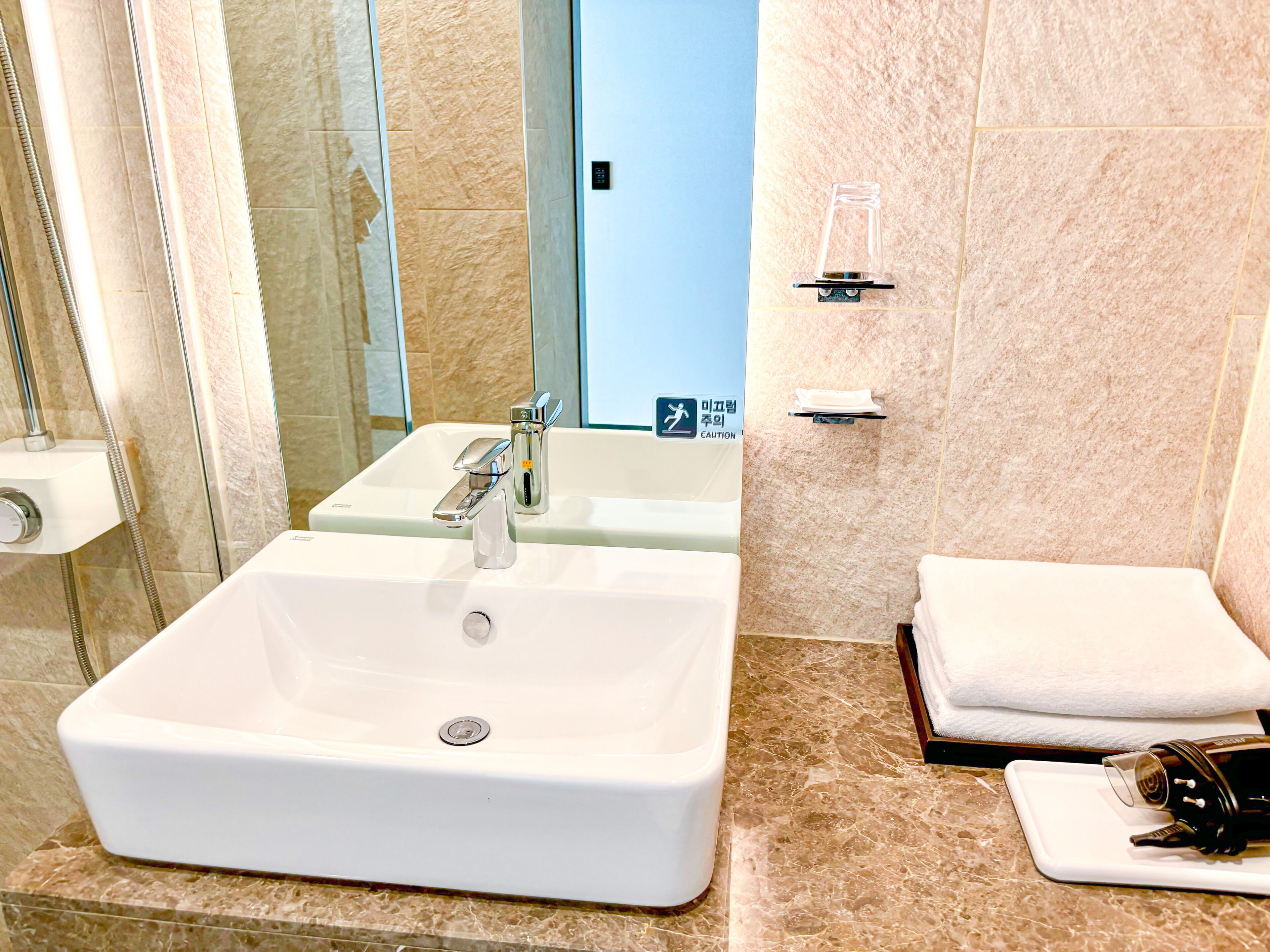 Casa de banho com lavatório branco, espelho e porta-toalhas.