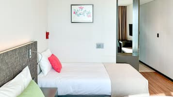 Quarto de hotel com duas camas, uma obra de arte emoldurada na parede e um espelho refletindo parte do espaço.