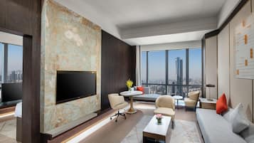 Uma sala de estar moderna com uma TV grande, assentos confortáveis, uma mesa de centro e vista para a cidade.