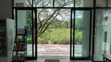 Entrada de hotel com porta de vidro, balcão de recepção e máquina de vendas automática.