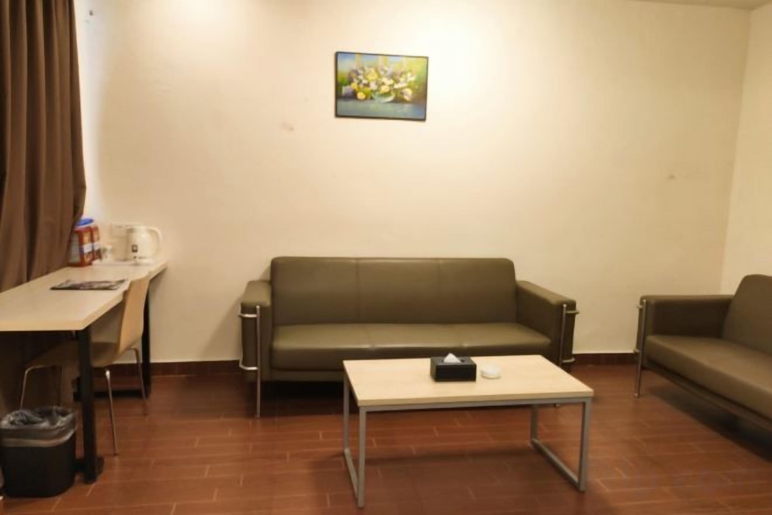 Quarto mobiliado com sofá, mesa, cadeira e um quadro na parede.