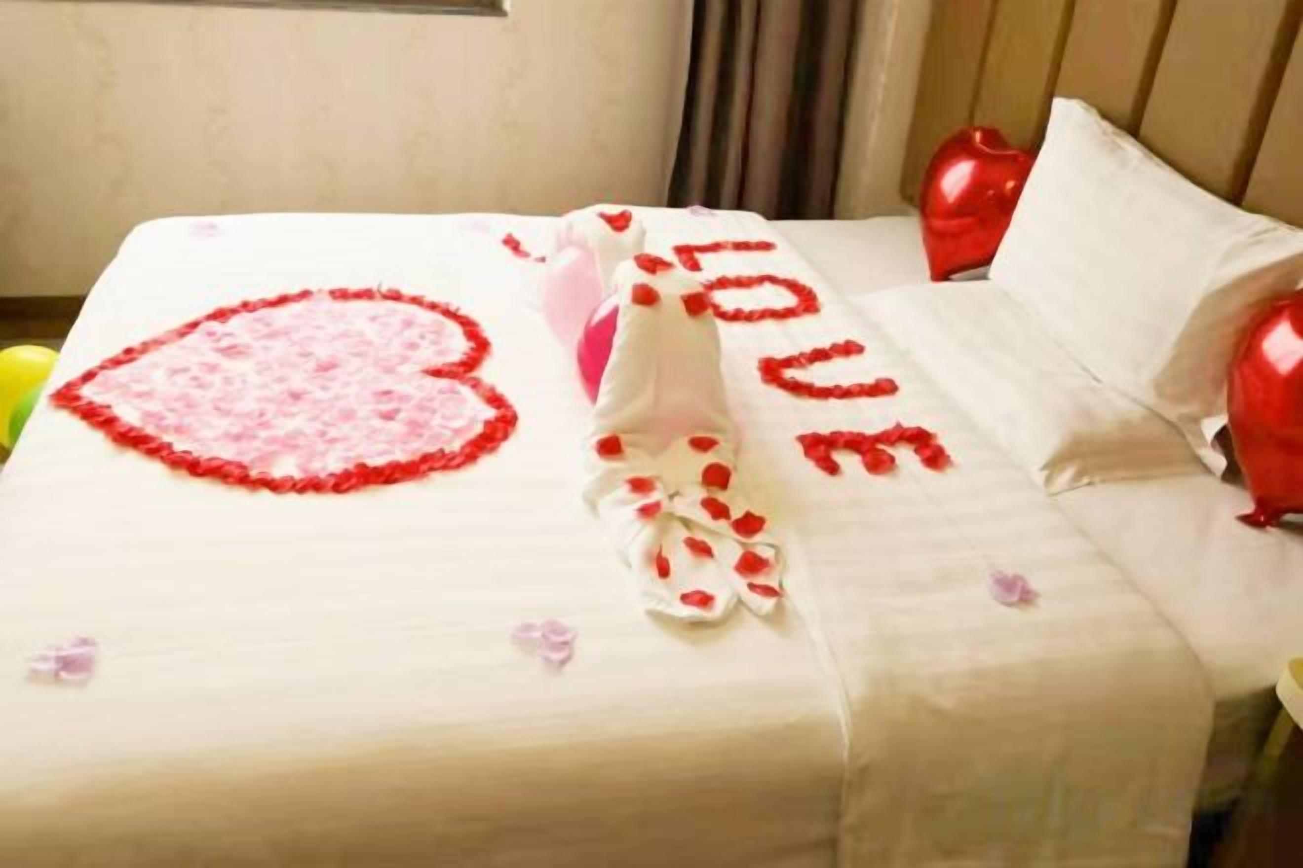 Uma cama com uma decoração em formato de coração e a palavra 'LOVE' escrita em vermelho.