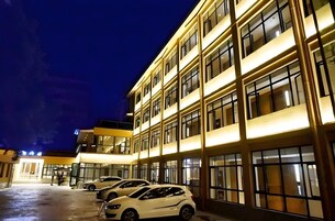 Edifício de hotel com vários andares e área de estacionamento em frente.