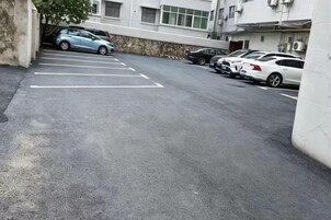 Um estacionamento com vários carros, um edifício com fachada de pedra e céu claro.