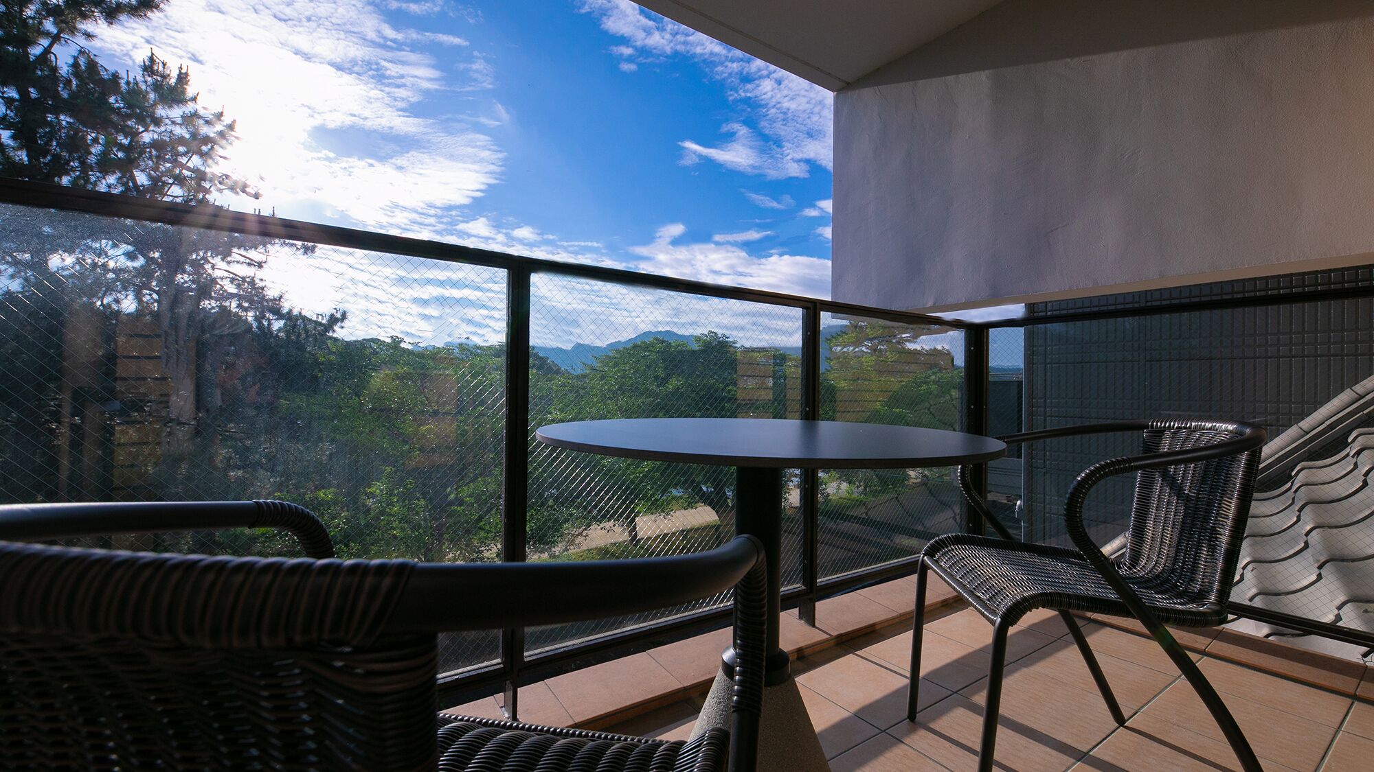 Uma varanda com mesa e cadeiras, com vista para árvores e montanhas.