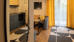 Uma sala de estar moderna com um espelho grande, uma área de jantar com cortinas amarelas e uma cozinha com armários de madeira.