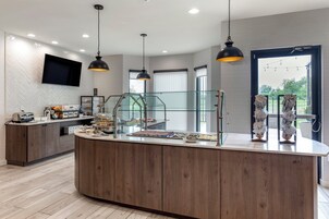 Cozinha moderna com ilha central, eletrodomésticos embutidos e uma grande janela que proporciona luz natural.