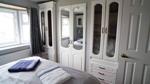 Quarto com cama, guarda-roupa e espelho.