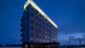 SuperHotel com design moderno, apresentando uma placa grande no topo, vários andares e uma área de entrada coberta.