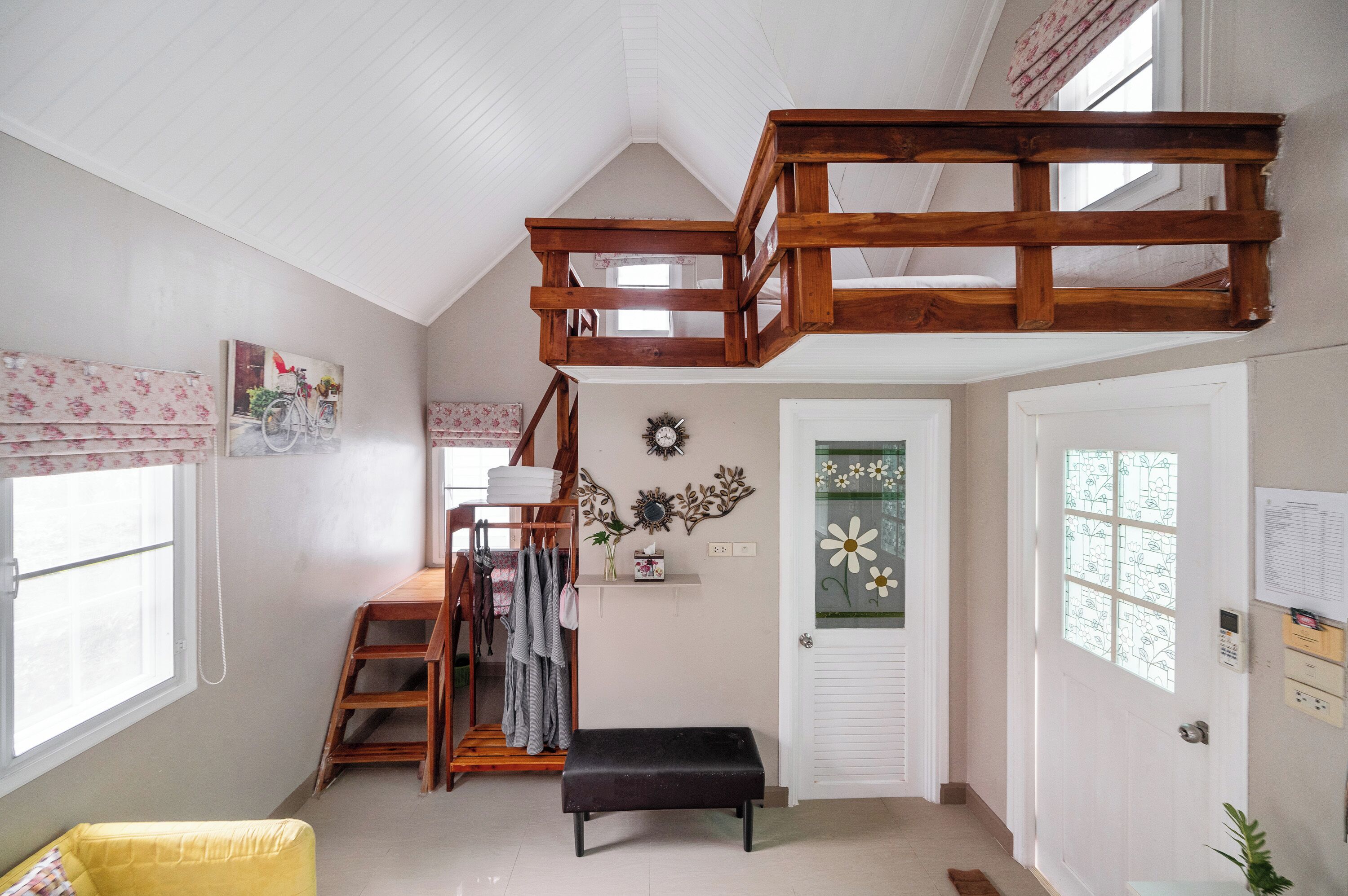 Quarto no estilo loft com cama beliche de madeira, um banco, uma escrivaninha e uma escada.
