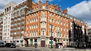 Um edifício de esquina com uma placa chamativa do 'Morton Hotel', apresentando uma fachada clássica de tijolos vermelhos com várias janelas e uma torre de canto.