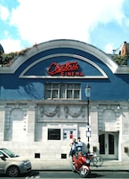 Um edifício com letreiro de neon que diz "Electric Cinema" e estilo arquitetônico clássico com detalhes decorativos.