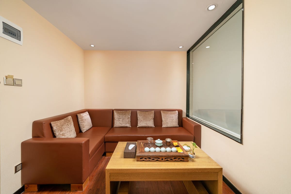 Uma sala de estar moderna com um sofá de couro marrom, uma mesa de centro de madeira e uma janela grande.