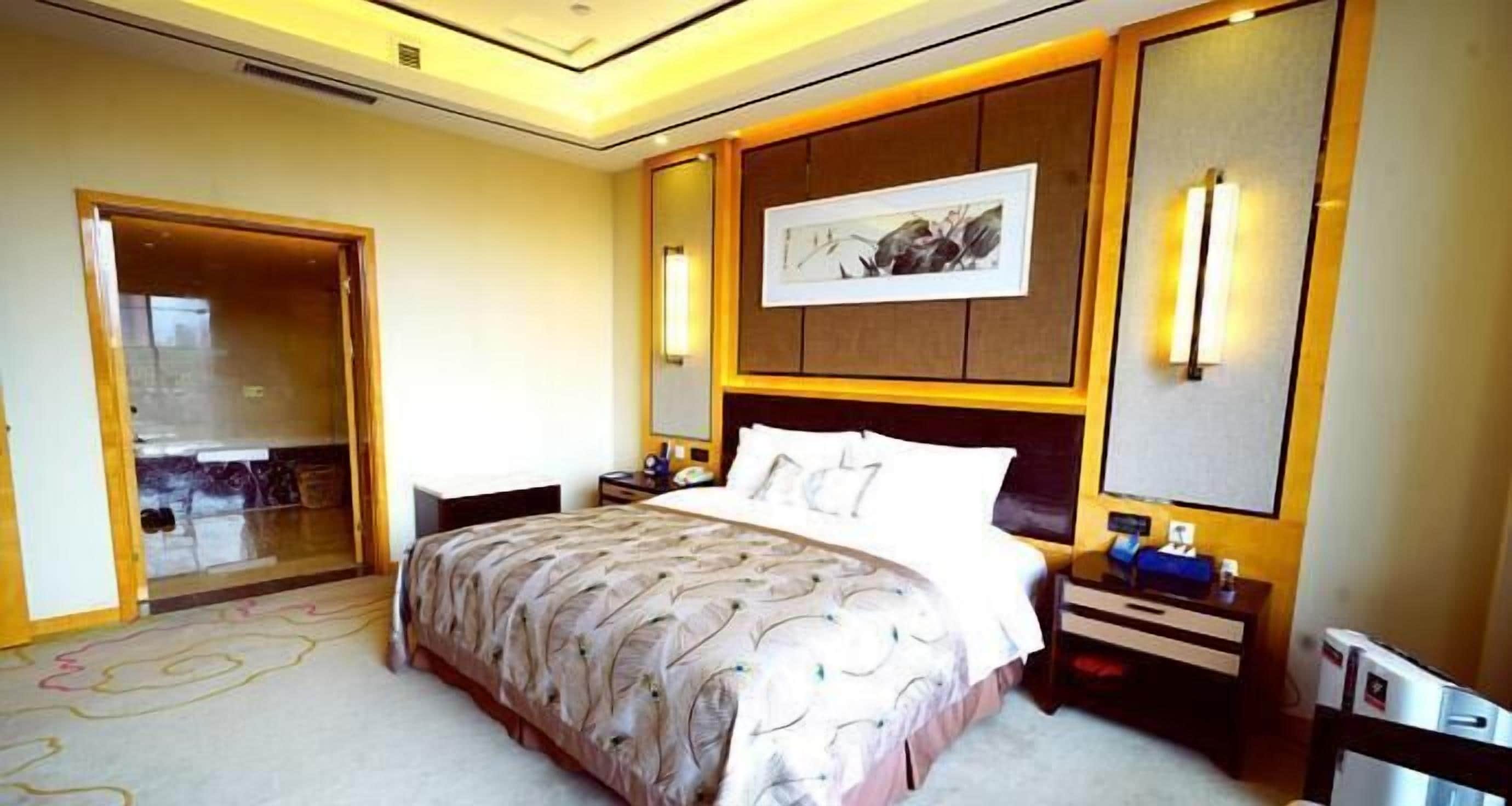 Quarto de hotel com uma cama grande, mesa de cabeceira, armário e um quadro na parede.