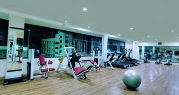 Academia com máquinas de cardio, equipamentos de musculação e uma grande bola de exercícios.
