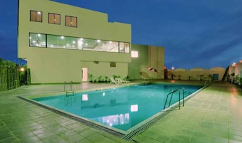Um edifício moderno com piscina, um terraço coberto e vista para a paisagem ao redor.