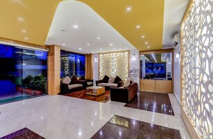 Um hall moderno com piso de mármore, sofás e divisória decorativa.