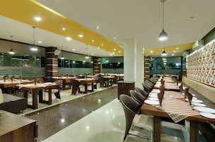 Um restaurante amplo com várias mesas e cadeiras, um corredor central e uma parede estampada em um dos lados.