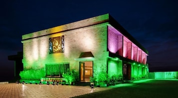 Um edifício moderno com uma grande placa iluminada, fachada de tijolos e área de entrada com iluminação verde.