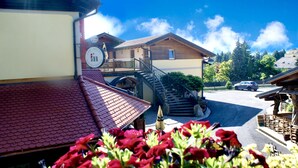 Um hotel com telhado de telhas vermelhas, escadaria que leva a uma varanda e placa indicando ser um hotel.
