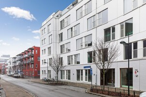 Um edifício residencial com vários andares, fachada branca, varandas e entrada visível.