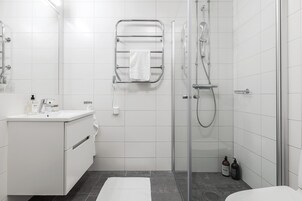 Um banheiro moderno com chuveiro em cabine de vidro, pia branca e porta-toalhas.