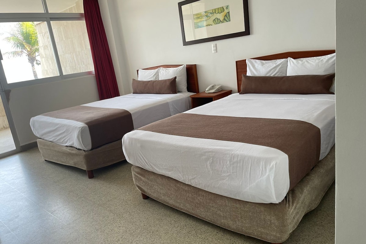 Quarto de hotel com duas camas, um telefone na mesa de cabeceira e um quadro pendurado na parede.