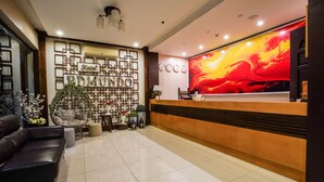 Uma área de recepção de hotel com design moderno, incluindo um balcão de atendimento, área de estar e painéis decorativos na parede.