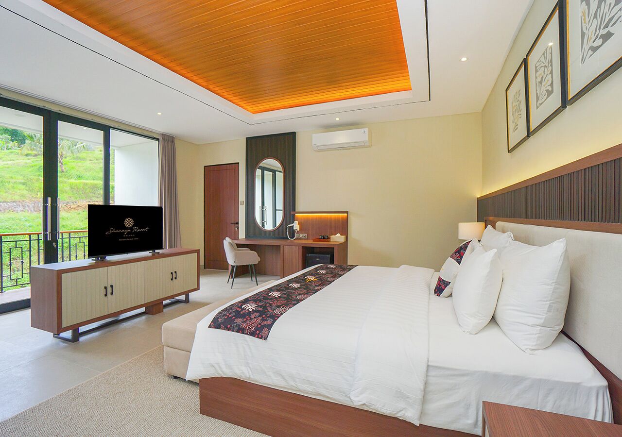 Quarto de hotel moderno com uma cama grande, uma escrivaninha e uma televisão.
