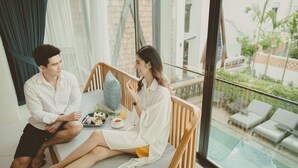Um casal sentado à mesa com vista para uma piscina e área externa.
