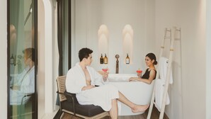 Quarto de spa com banheira, duas garrafas de álcool e uma escada.