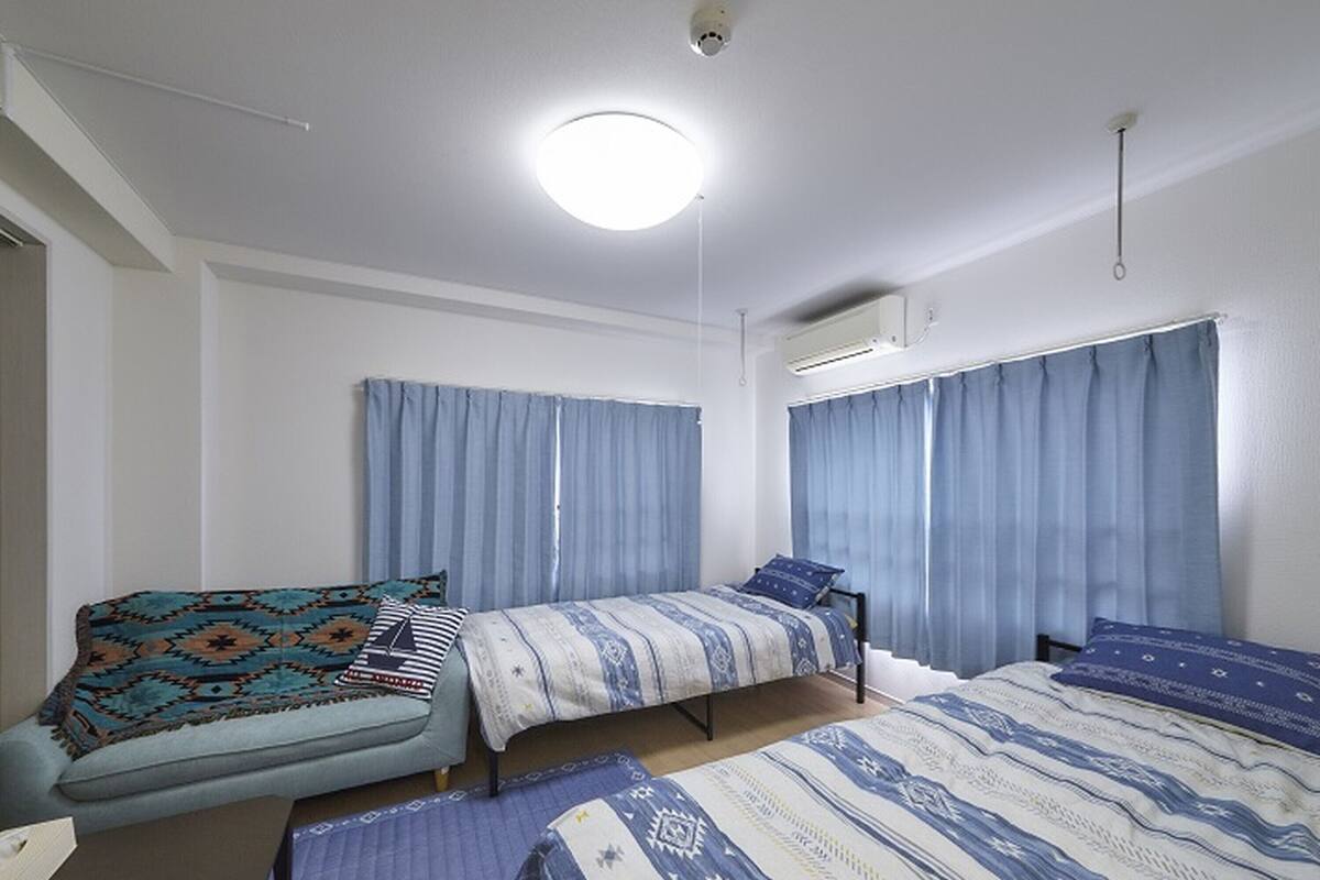 Quarto com duas camas, um sofá e um ventilador de teto.
