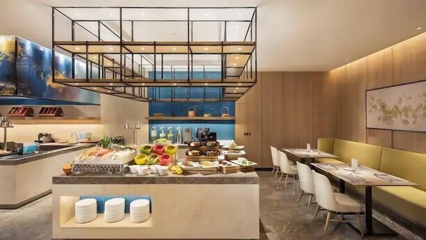Um hall de hotel moderno com um buffet central, áreas de estar e vista para o oceano.