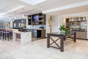 Uma cozinha moderna com bancada de mármore, uma ilha central com banquetas e uma mesa de jantar.