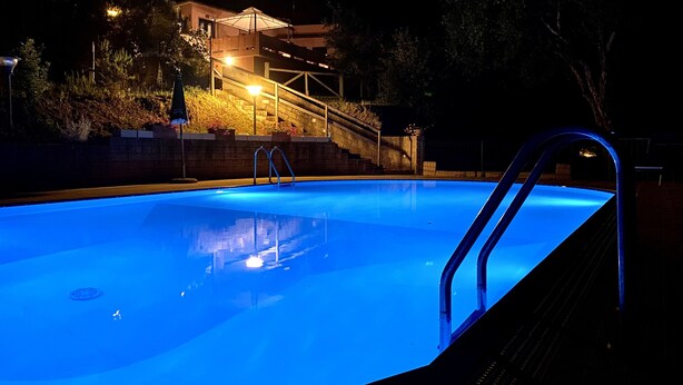 Piscina à noite com vista clara da área circundante, incluindo uma escadaria e um edifício ao fundo.