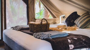 Um quarto aconchegante com uma cama, um cesto e vista para o verde pela janela.
