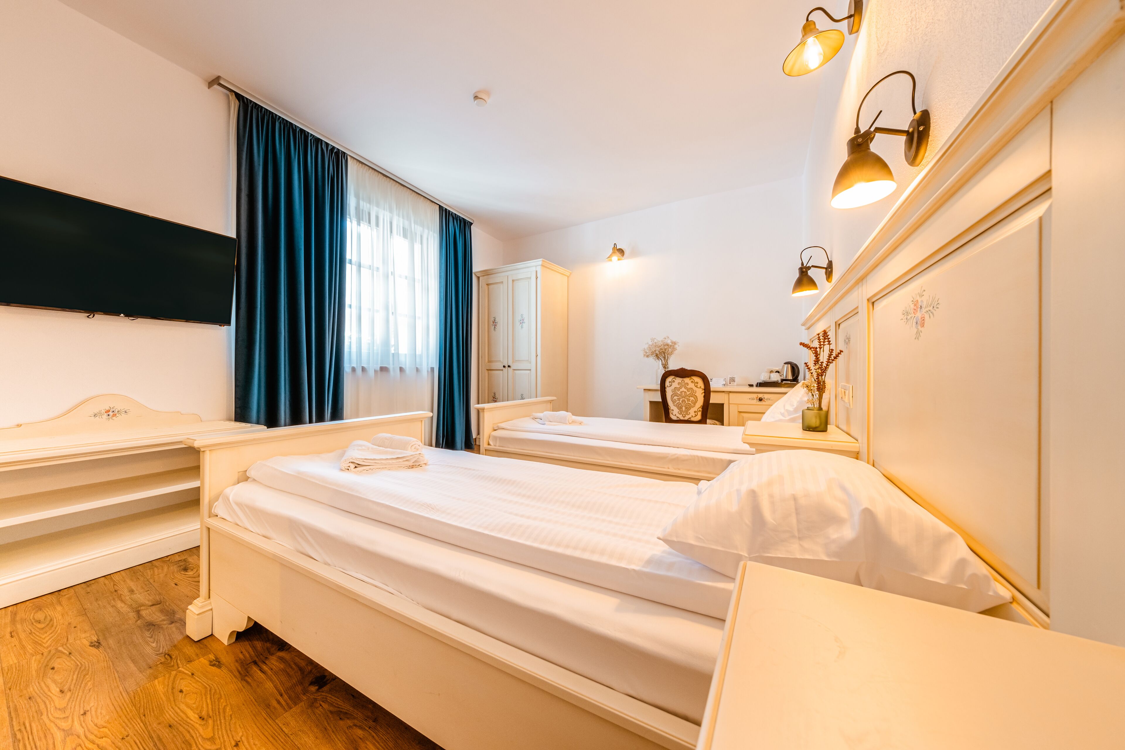 Quarto de hotel com duas camas, uma escrivaninha, televisão de tela plana e um espelho.