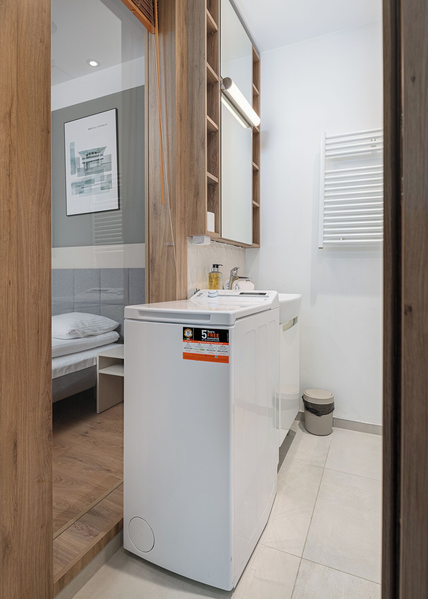 Casa de banho compacta e moderna, com máquina de lavar embutida, um lavatório pequeno e uma sanita.