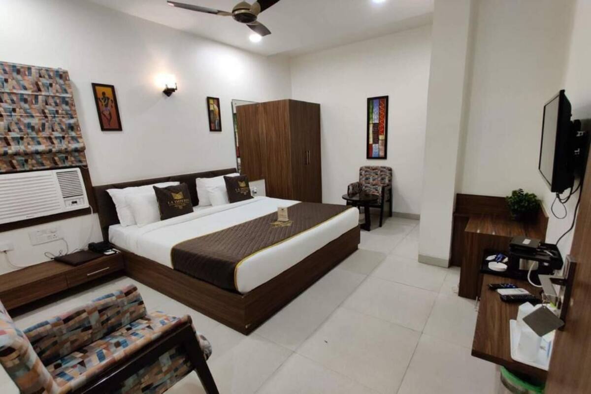 Quarto de hotel com uma cama, uma escrivaninha, uma cadeira, um guarda-roupa e uma televisão.