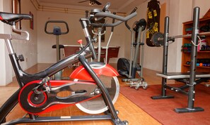 Uma bicicleta ergométrica, um banco de musculação e um saco de pancadas em uma academia.