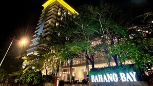 Entrada de hotel com uma placa indicando "BAHANG BAY HOTEL" e um edifício bem iluminado ao fundo.