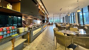 Um restaurante moderno de hotel com um balcão comprido, área de estar e grandes janelas.