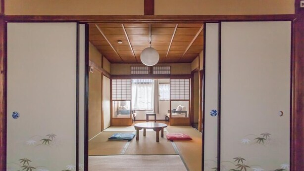 Um quarto japonês tradicional com tatames, uma mesa baixa e portas deslizantes com desenhos de bambu.