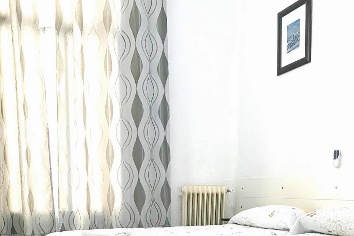Quarto com duas camas, um radiador e um quadro na parede.