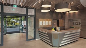 Uma receção com design moderno, uma parede de madeira com o nome 'Landhotel Beck' e entrada por uma porta de vidro.