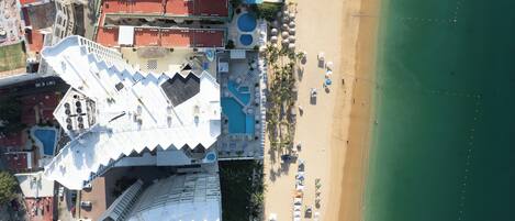 Vista aérea de um resort com piscina, praia e vários edifícios.