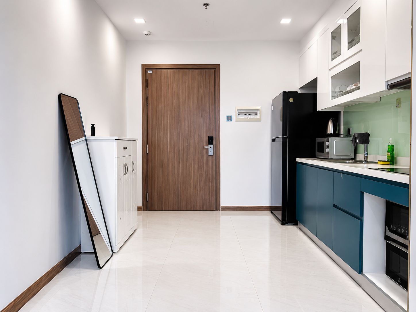 Cozinha moderna equipada com micro-ondas, forno e máquina de lavar loiça.