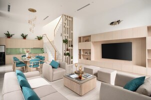 Uma sala de estar moderna com um sofá, uma mesa de centro, uma televisão e uma escadaria.