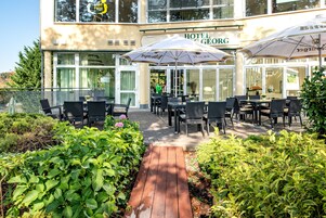 Pátio de hotel com área de estar ao ar livre e caminho de madeira.